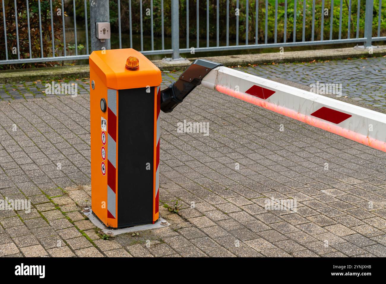 An automatic barrier stands at the entrance of a parking lot, featuring ...