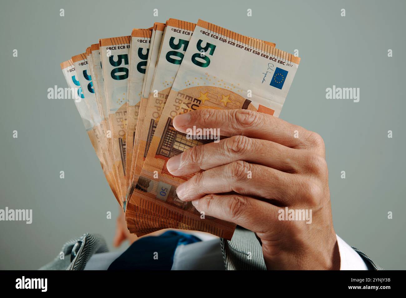 a businessman, wearing an elegant gray suit, shirt and tie, has some ...