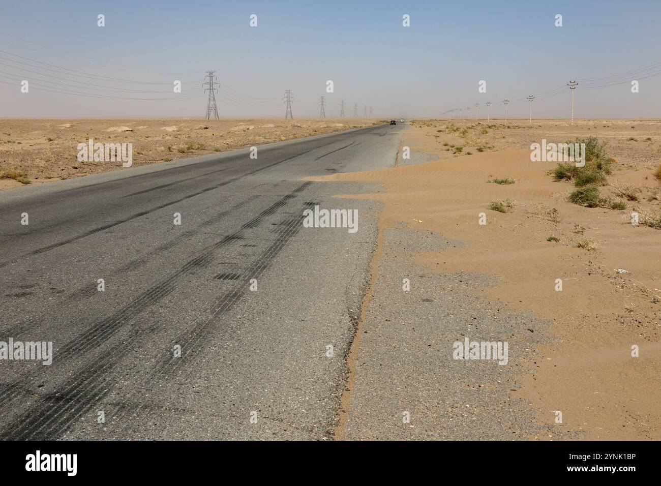 A long, paved road stretches through a dry desert landscape in ...
