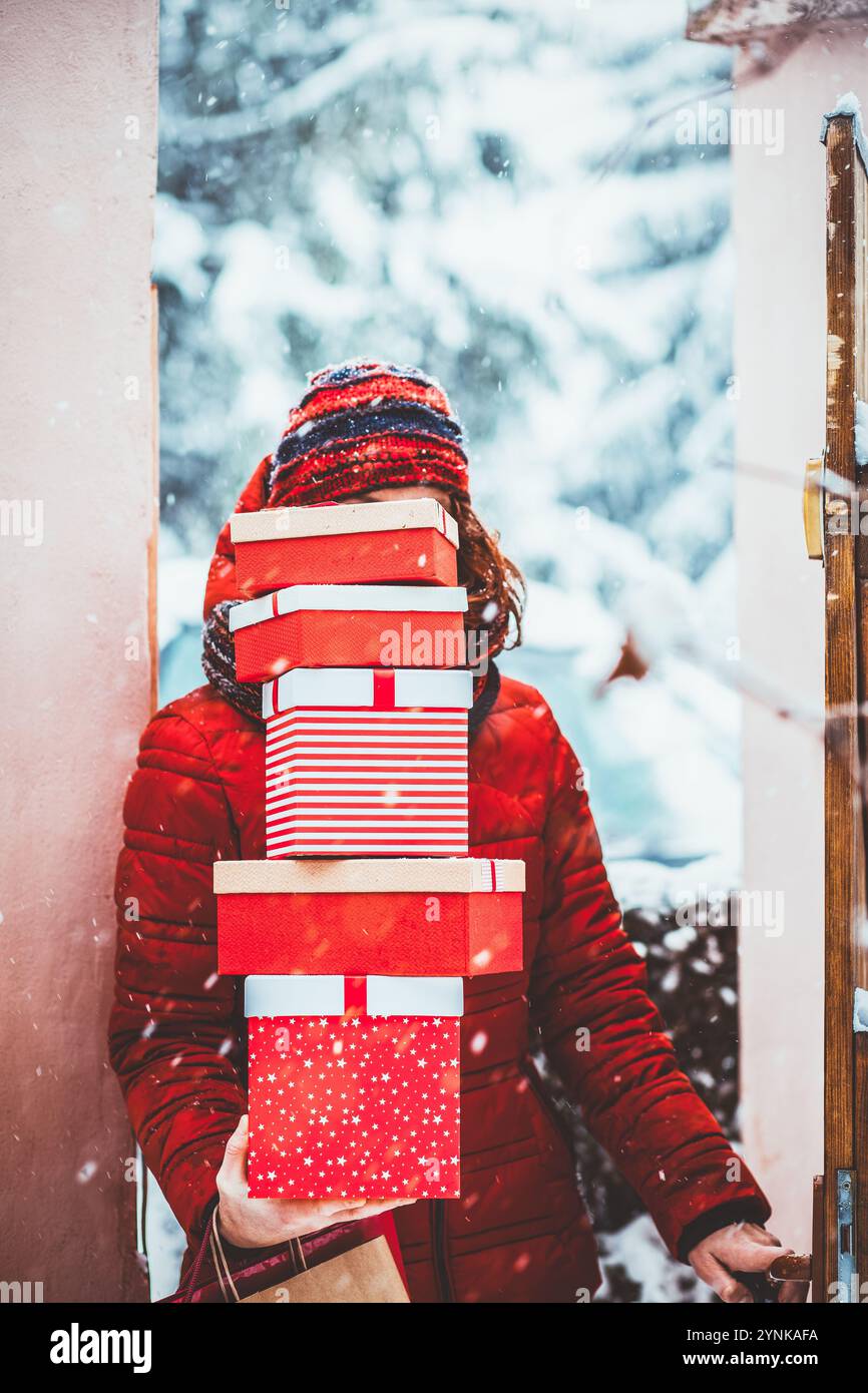 woman returning home from shopping holding pile of christmas present ...