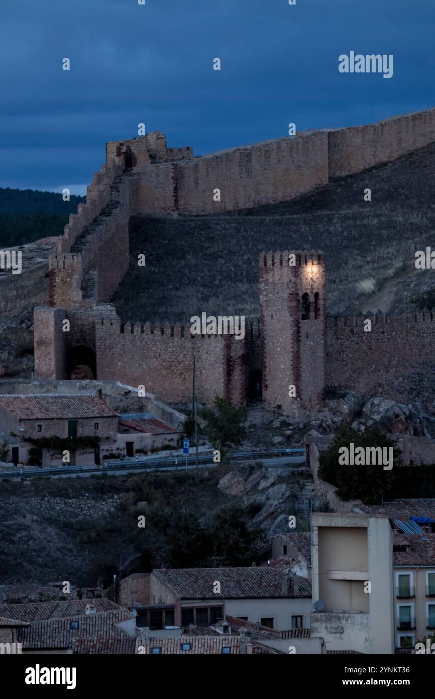 Illuminated medieval watchtower and stone walls at dusk with rustic ...