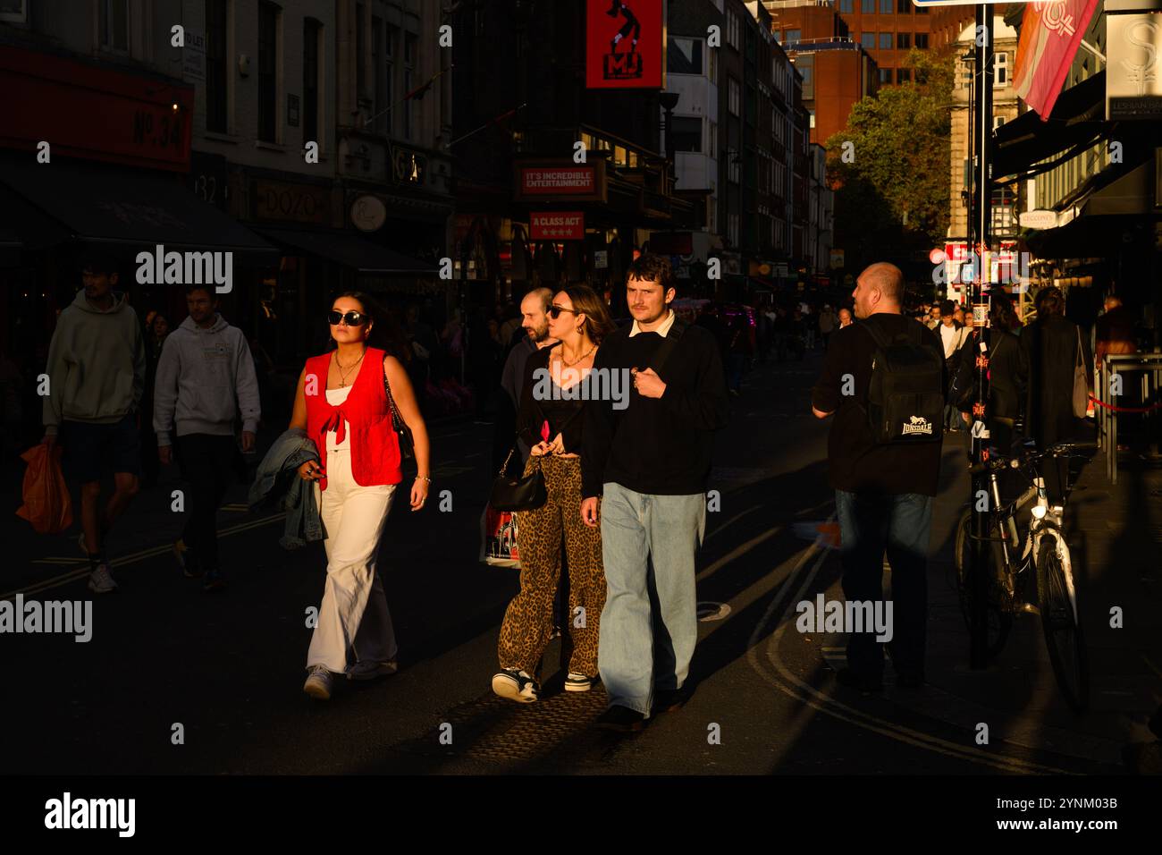 People walking along Old Compton Street in the late afternoon sunlight ...