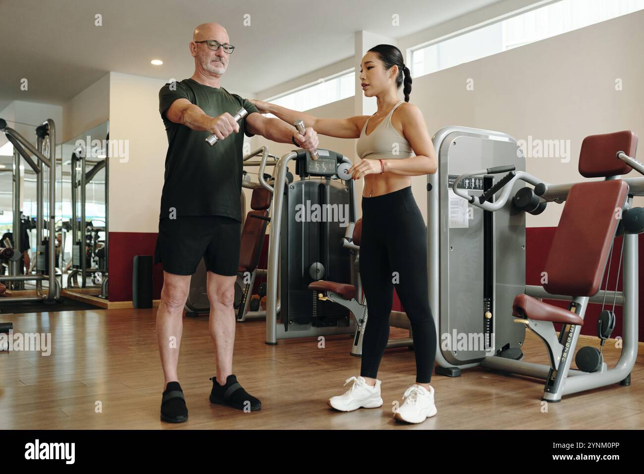Personal Trainer Assisting Man during Gym Workout Session Stock Photo ...