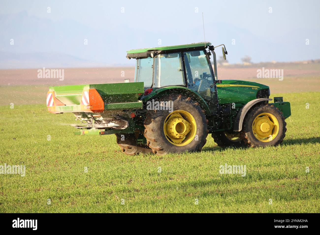 Fertilizer spread on a crop field by a tractor using a hopper Stock ...