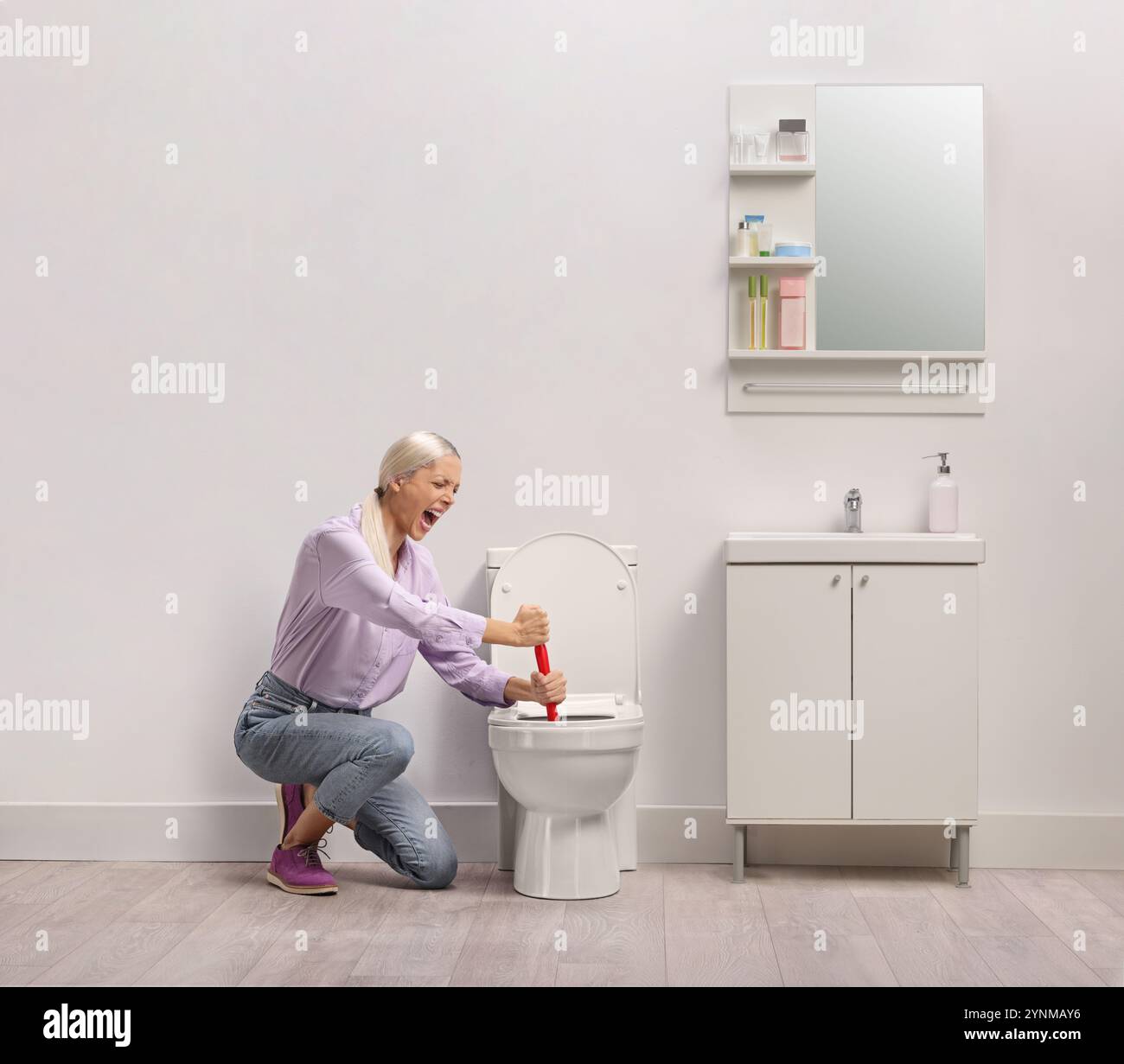 Angry woman unclogging a toilet with a plunger in a bathroom Stock ...