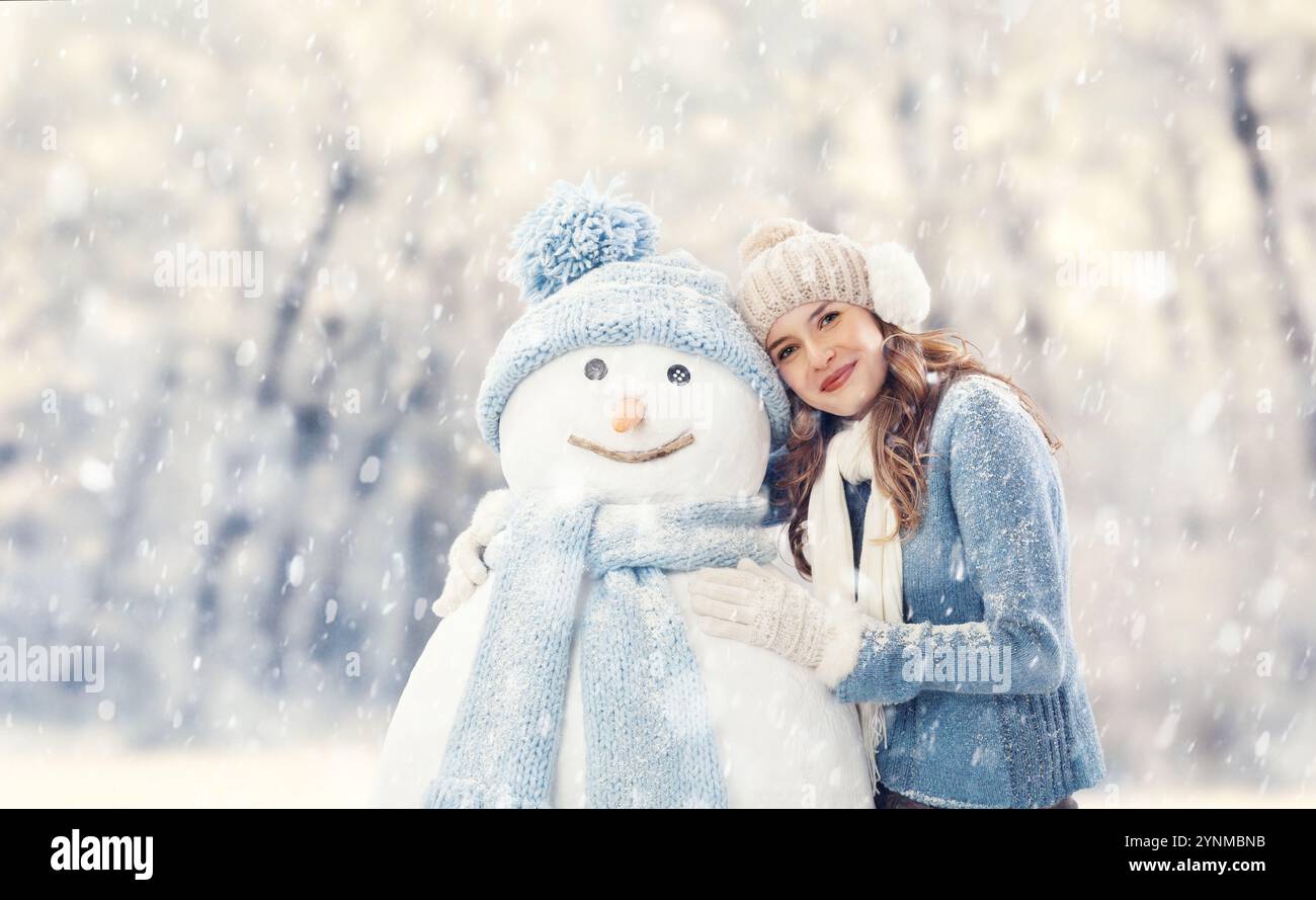 Happy young woman enjoying embracing a snowman in a winter snowfall ...