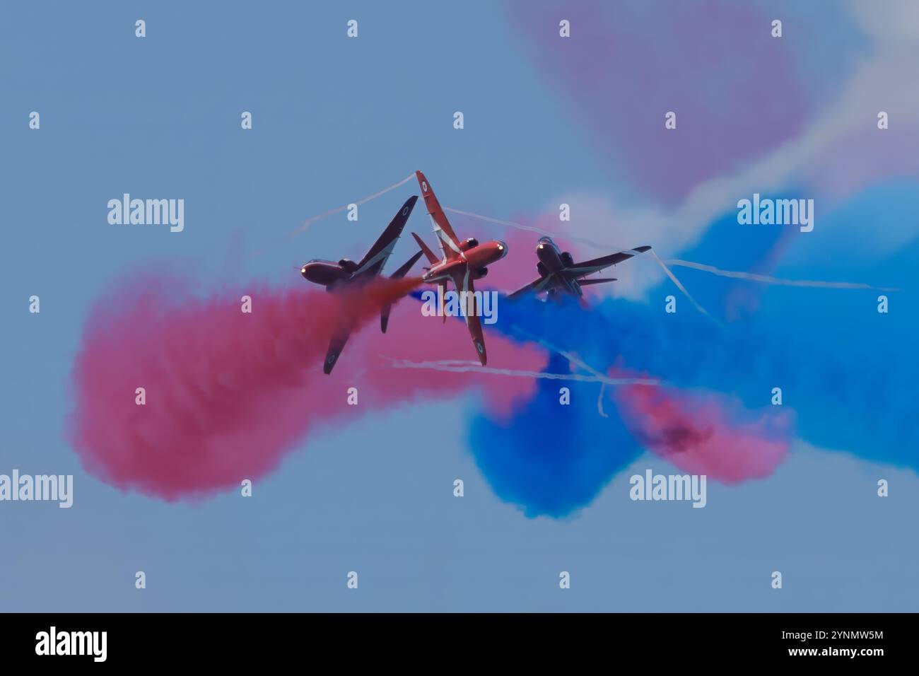 The Red Arrows perform a daring crossing maneuver, leaving dramatic red ...