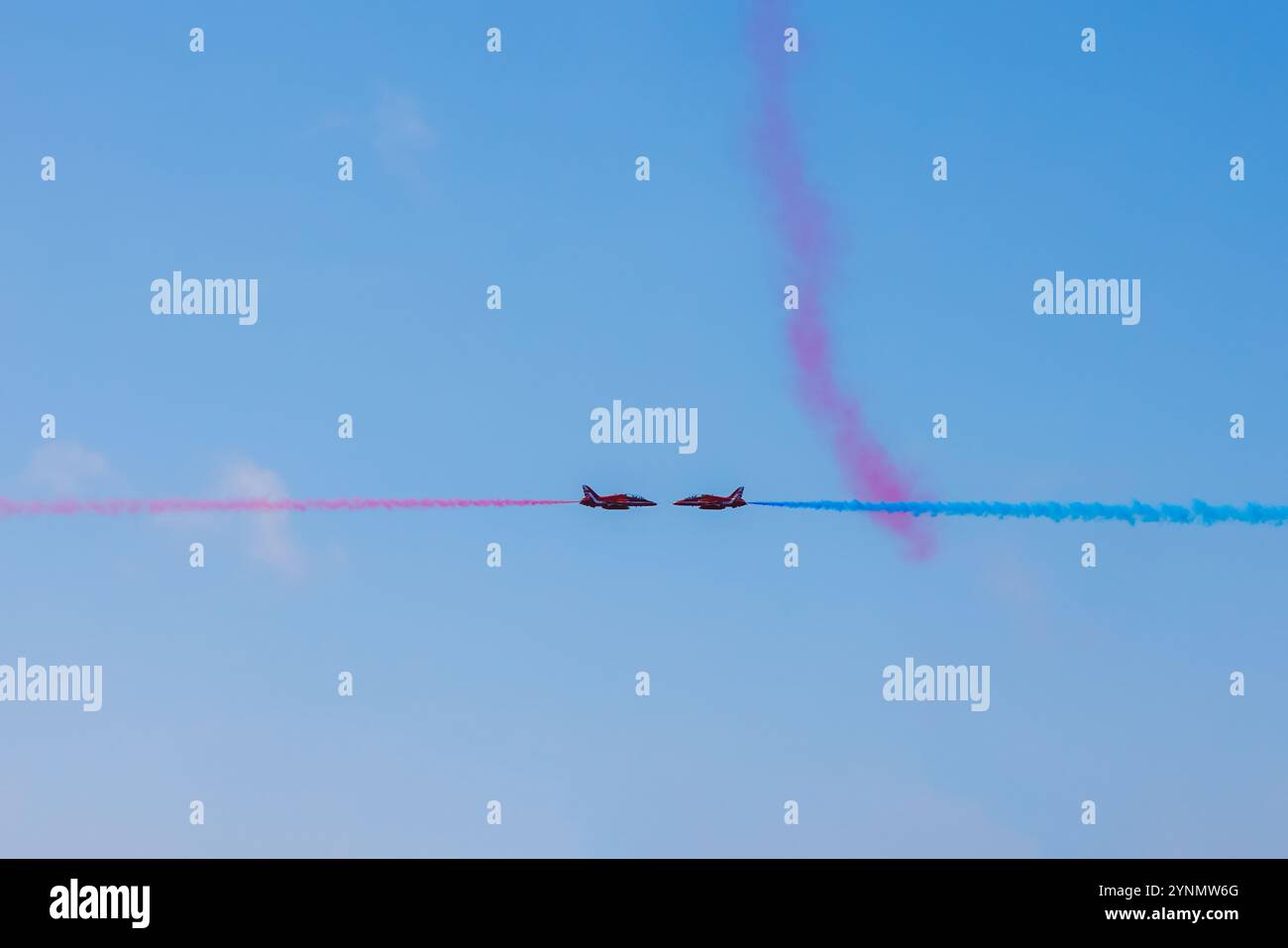 Two Red Arrows jets perform a daring cross-over maneuver, trailing ...