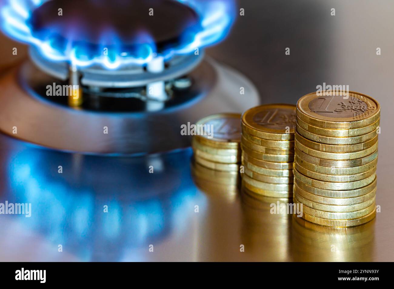 Gas stove lit, with stacks of coins above it. Increase in gas costs and ...