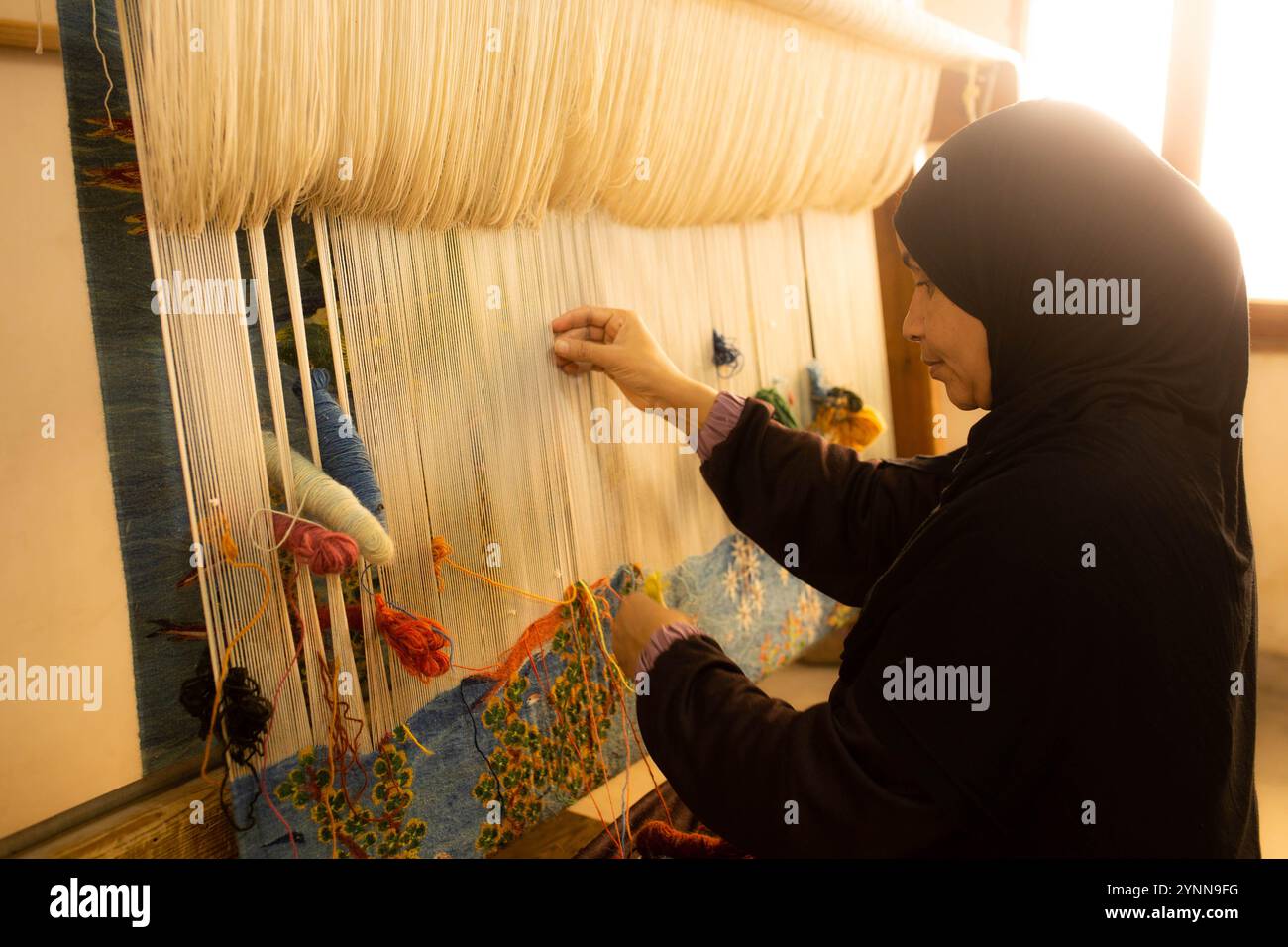 A worker making her handmade carpet Stock Photo - Alamy