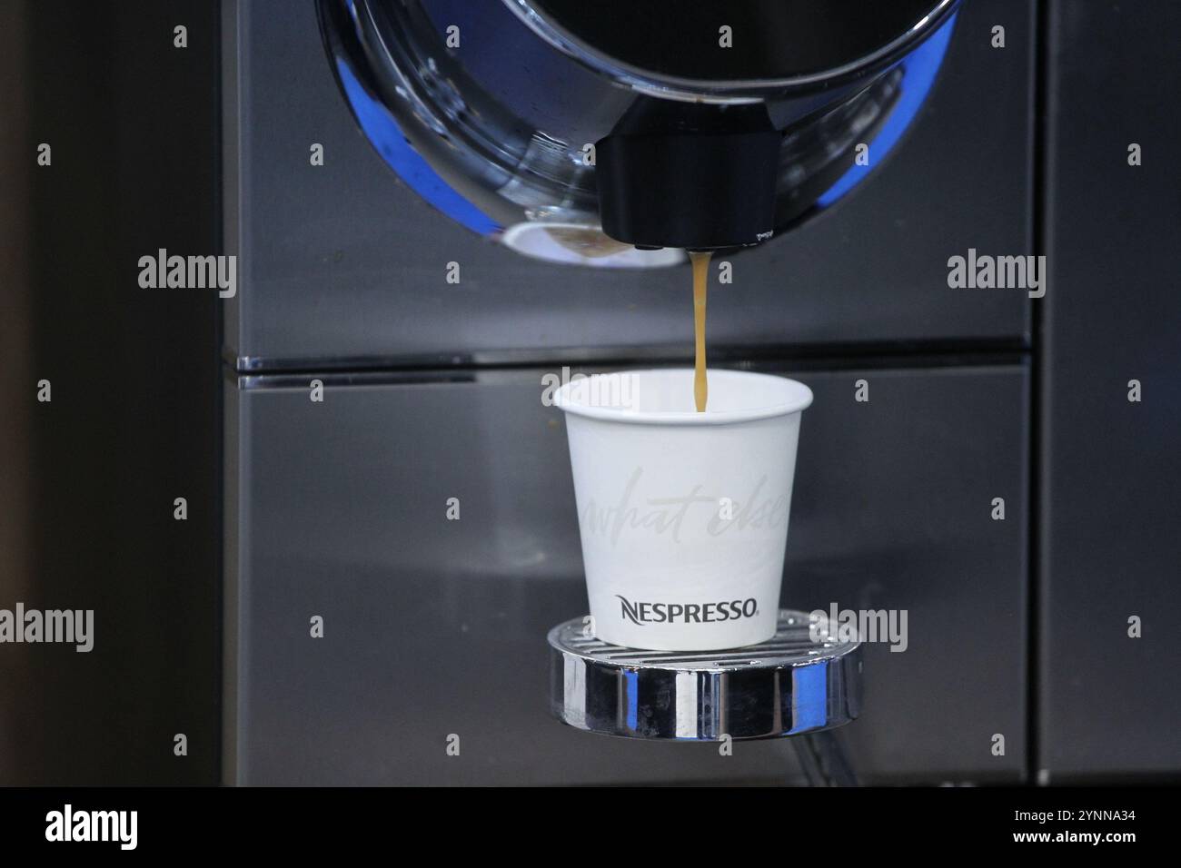 Fresh espresso dripping into a Nespresso-branded paper cup Stock Photo ...