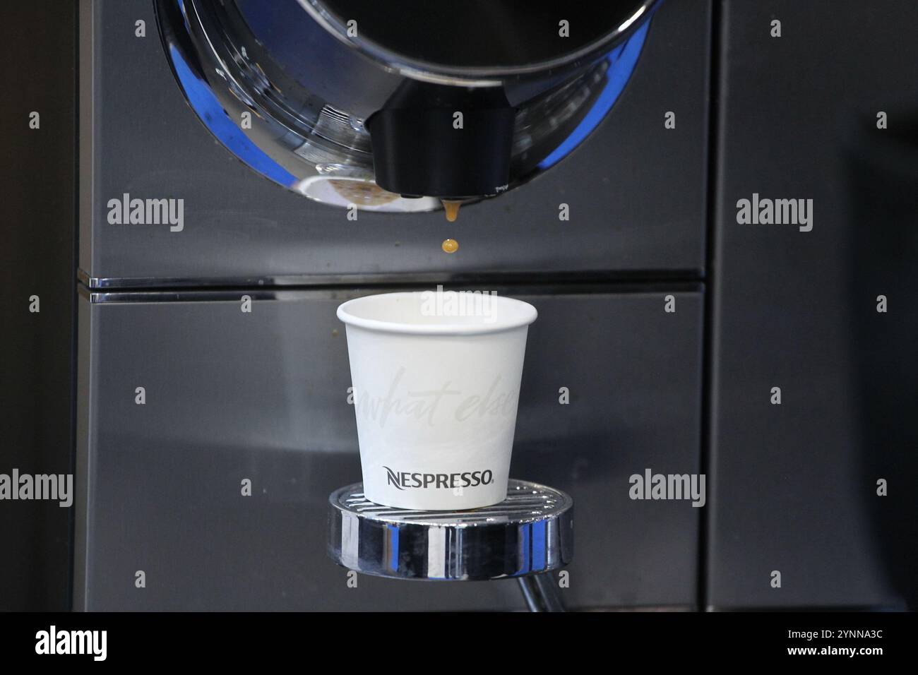 Fresh espresso dripping into a Nespresso-branded paper cup Stock Photo ...