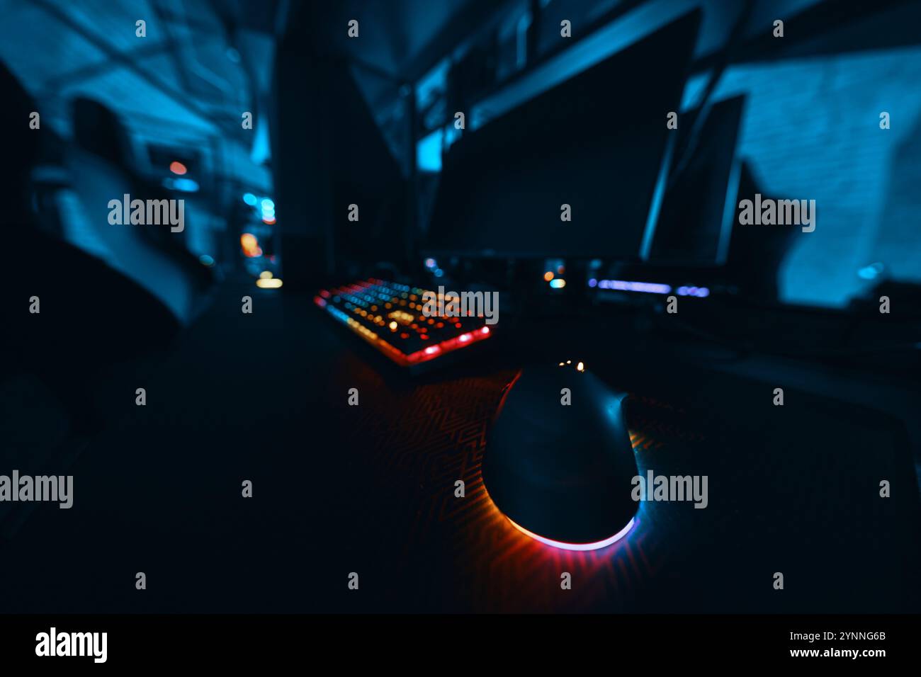 Computer setup featuring a colorful keyboard and mouse in a dimly lit ...