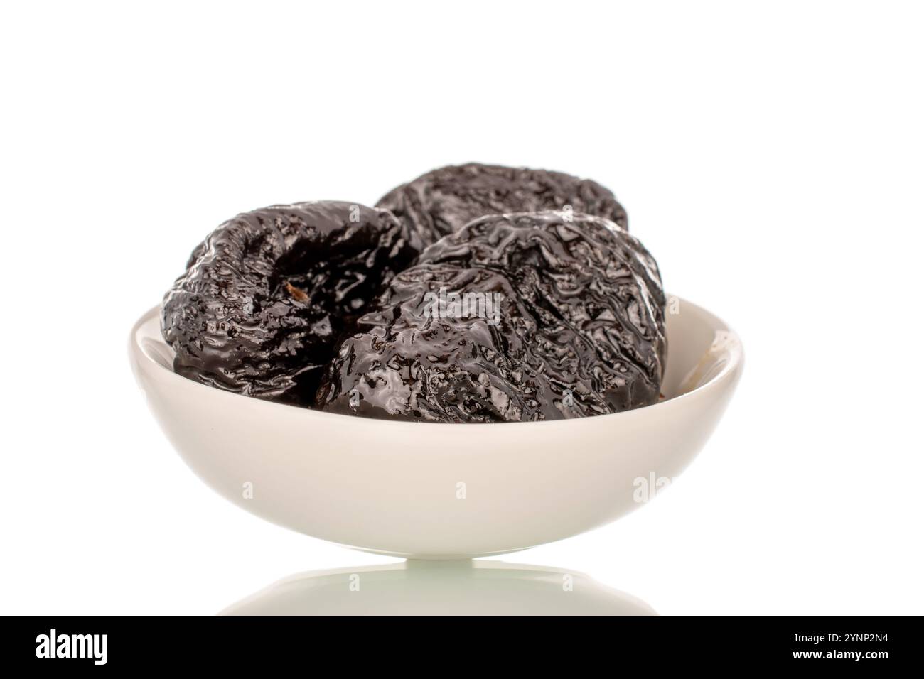Sweet prunes in a ceramic bowl, macro, isolated on a white background ...
