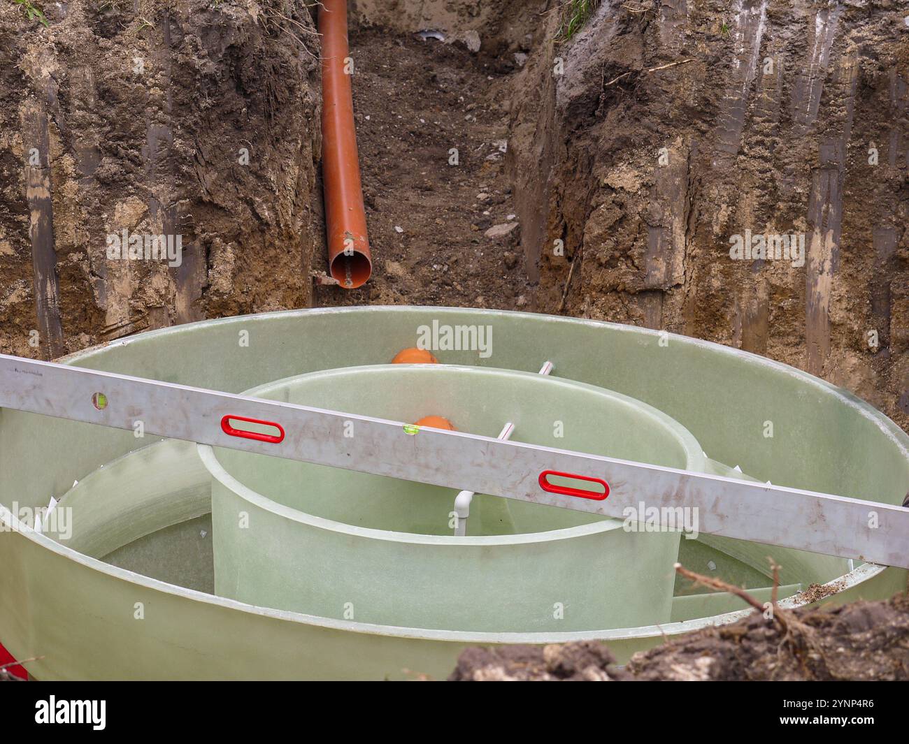 A large green septic tank being installed in a freshly excavated pit ...