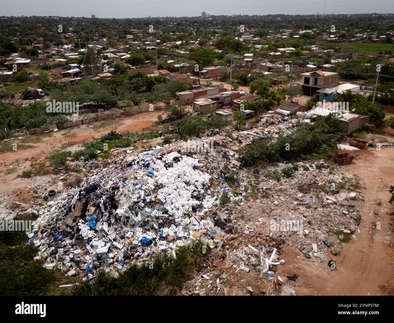 Plastic waste piles up in the backyard of a home where a family ...