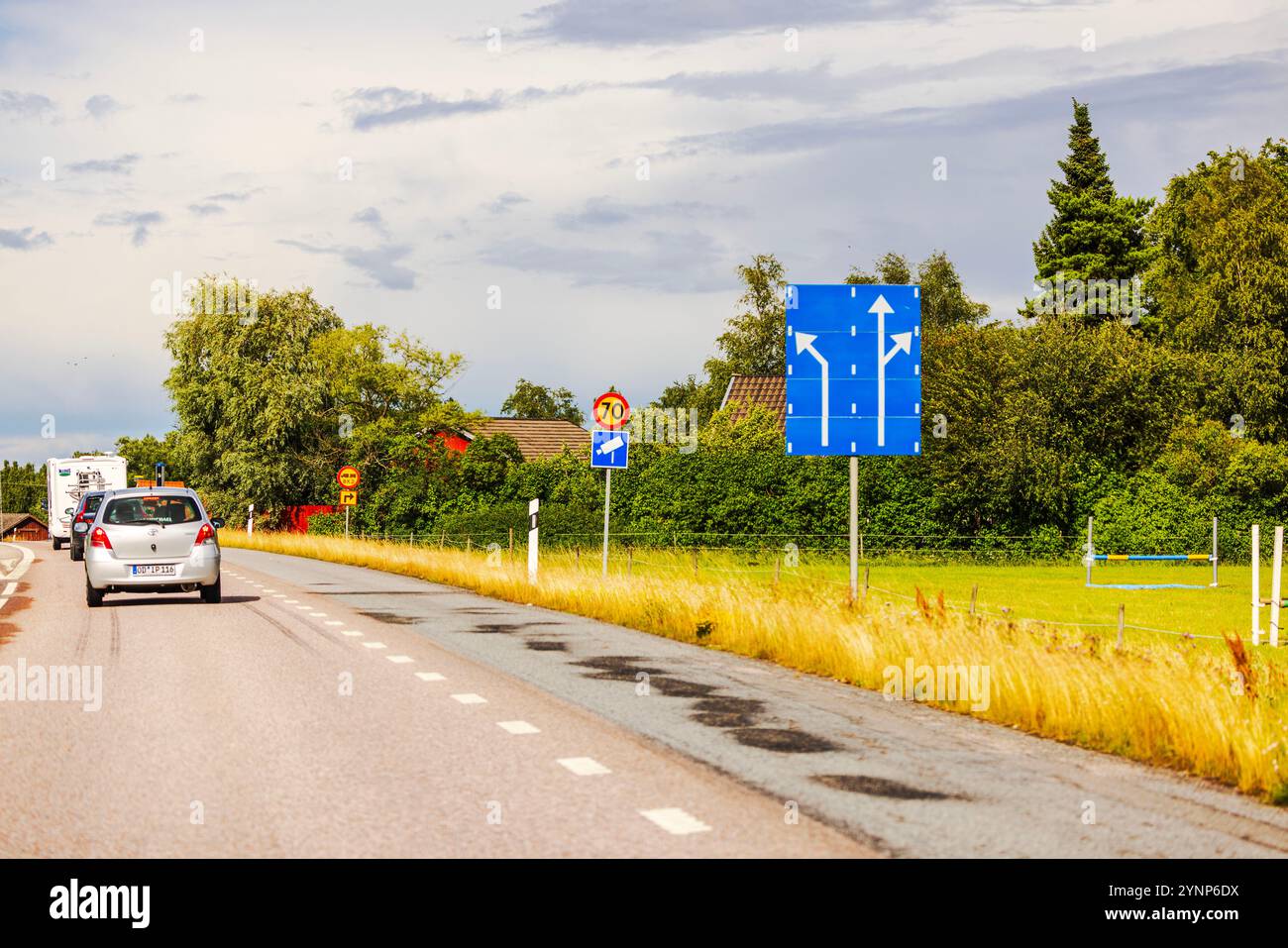 Highway in rural area with moving cars, road signs and green vegetation ...
