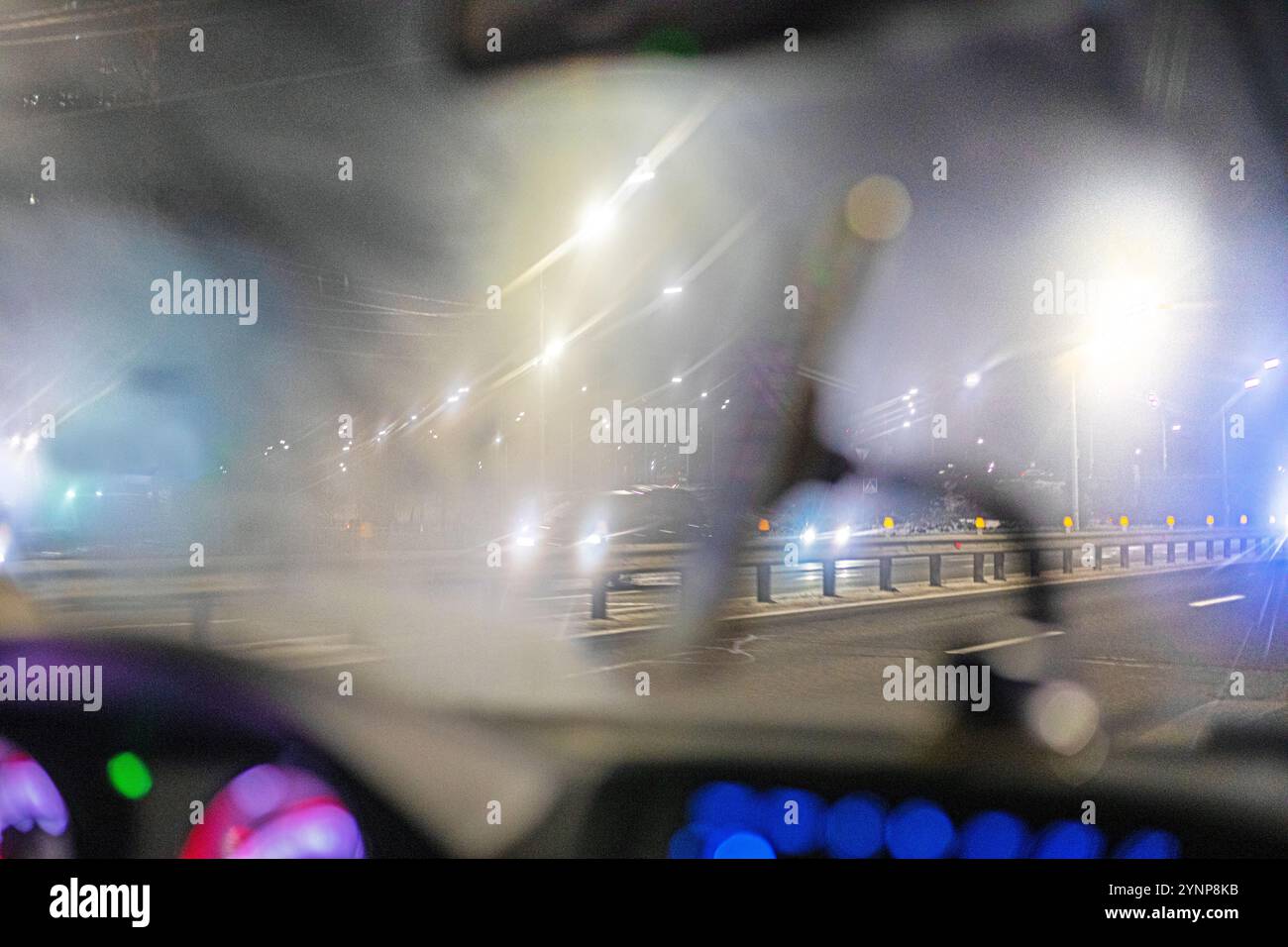 fogged car windshield in evening lights while driving. Poor visibility ...