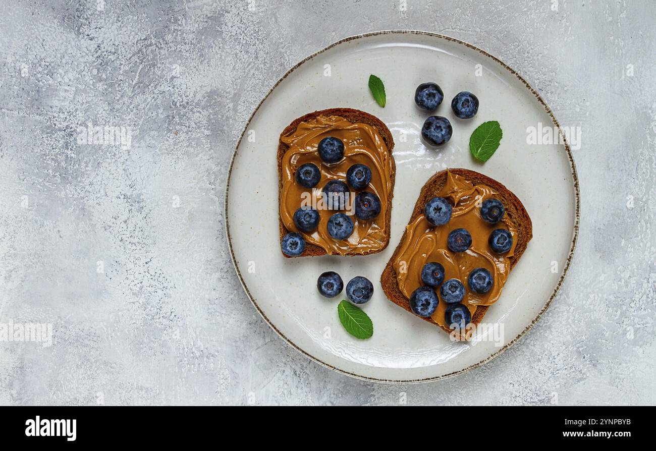 Rye bread with peanut paste and fresh blueberries, top view, no people ...