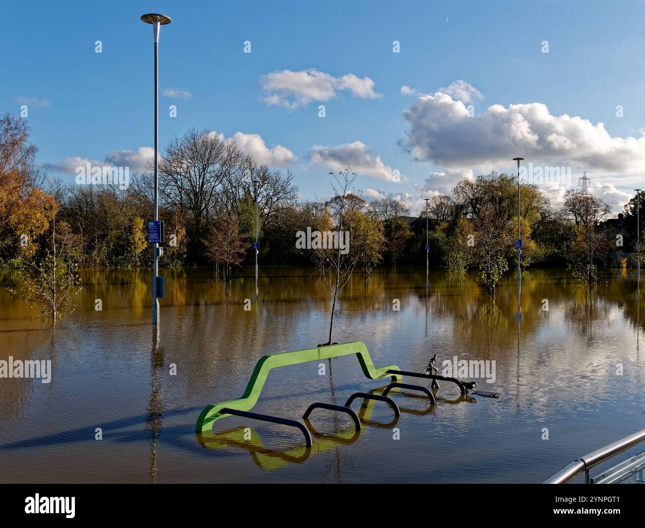 Flooded parking lot with submerged bicycle rack and reflected trees at ...