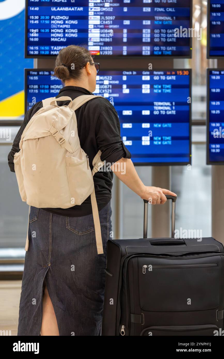 Traveler checking flight details on an airport departure board with ...