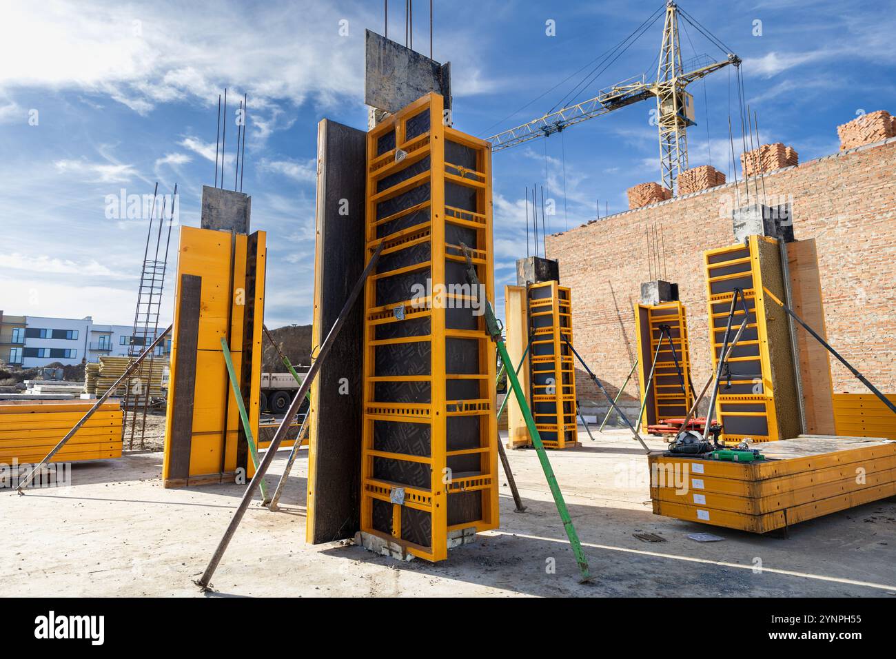 Construction site with yellow column formwork and brick wall, ready for ...