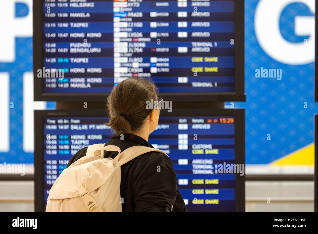 Traveler checking flight information on an airport departure board ...