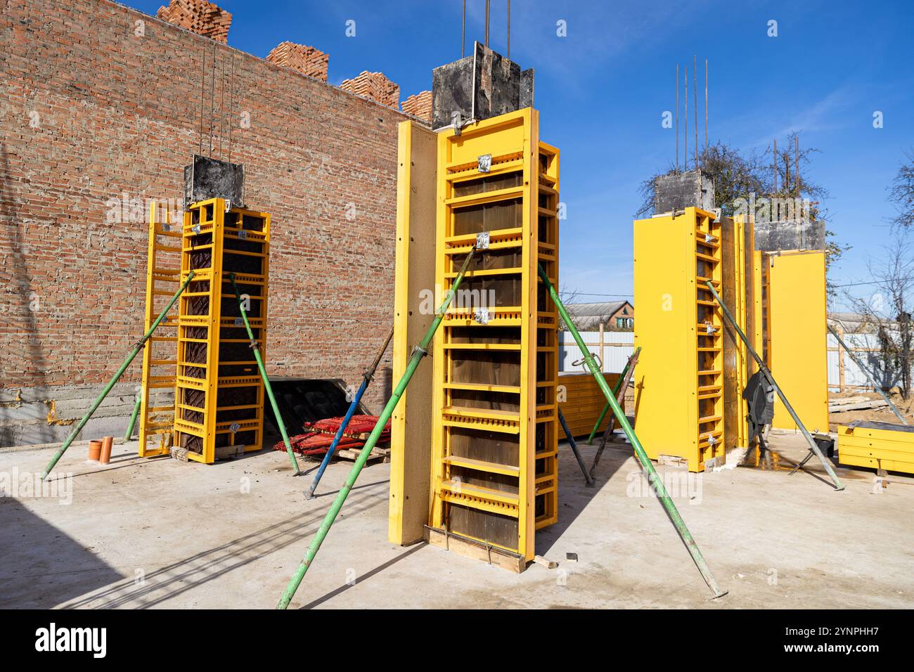 Construction site with yellow column formwork and brick wall, ready for ...