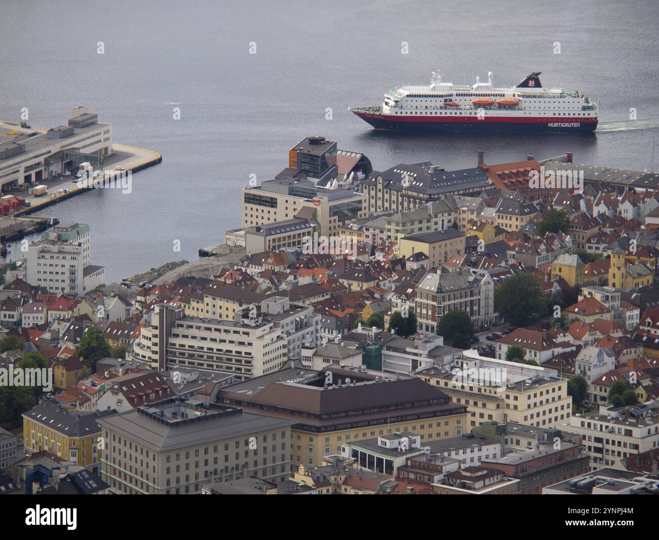 A large ship sails through a city harbour, surrounded by a mix of urban ...