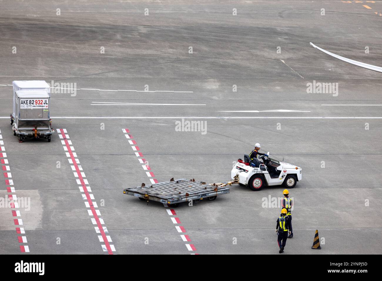 Ground crew operating a utility vehicle towing a cargo pallet on the ...