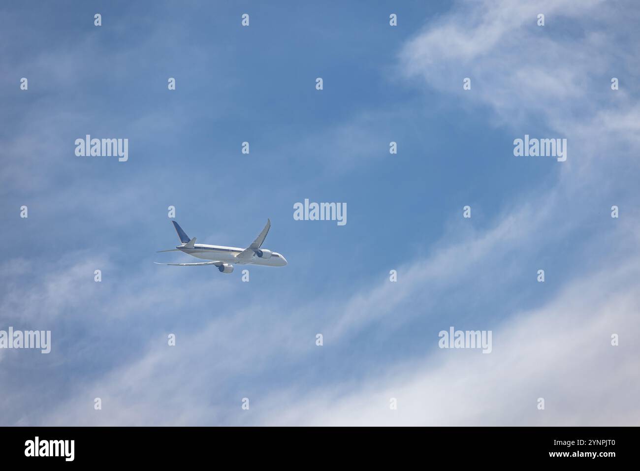 Commercial airplane cruising through the clear blue sky with wispy ...