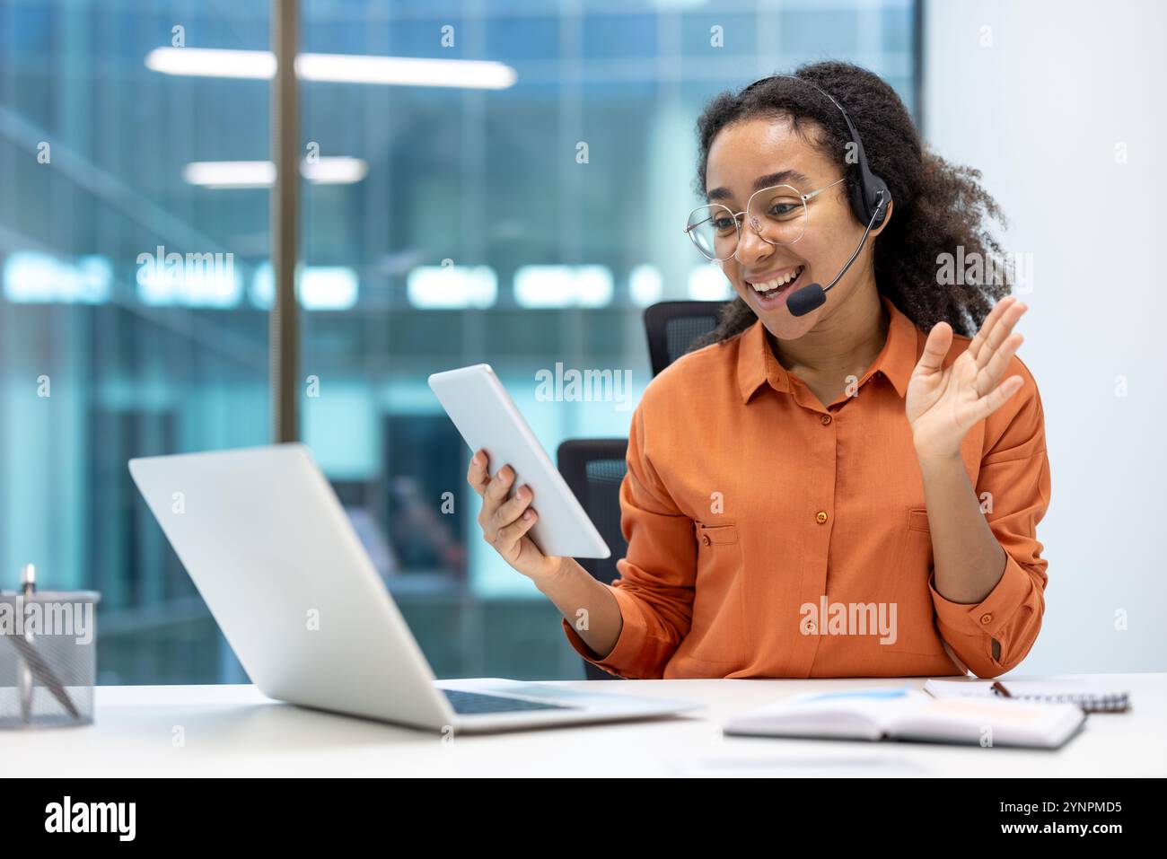 Office worker using smartphone and laptop with headset in modern ...