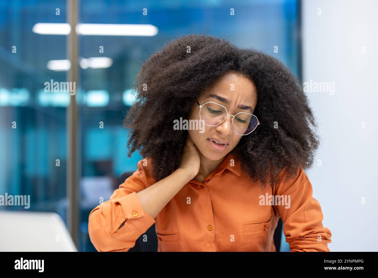 Office worker rubs neck, expressing stress or fatigue. Modern office ...