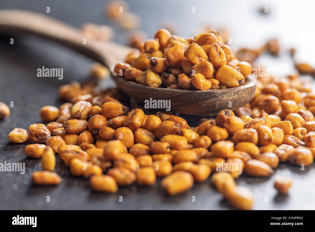 Roasted salted corn snack on spoon on a black table Stock Photo - Alamy