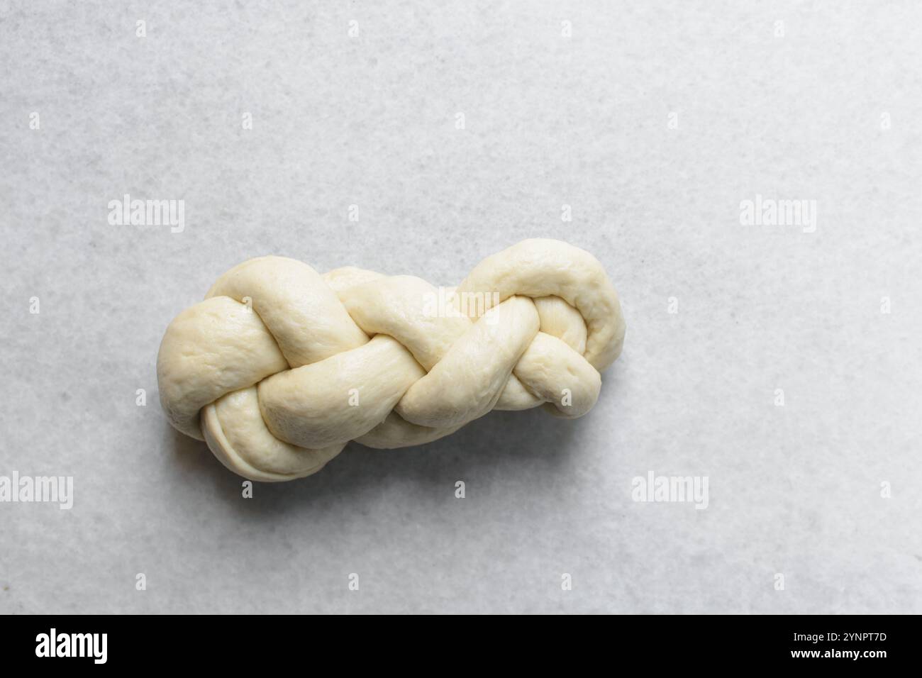 Overhead view of 2 strand challah rising on a parchment lined baking ...