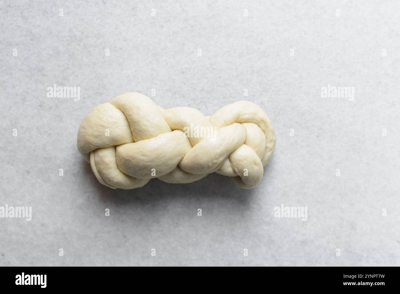 Overhead view of 2 strand challah rising on a parchment lined baking ...