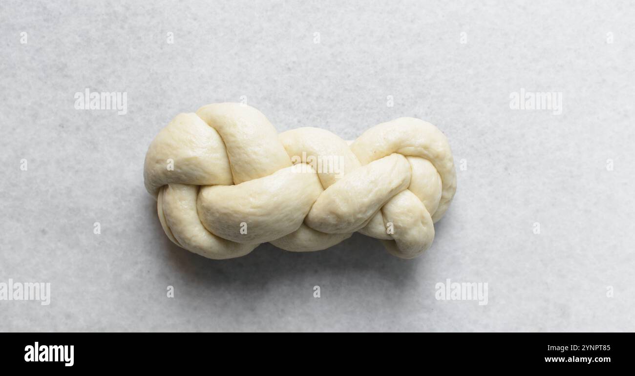 Overhead view of 2 strand challah rising on a parchment lined baking ...