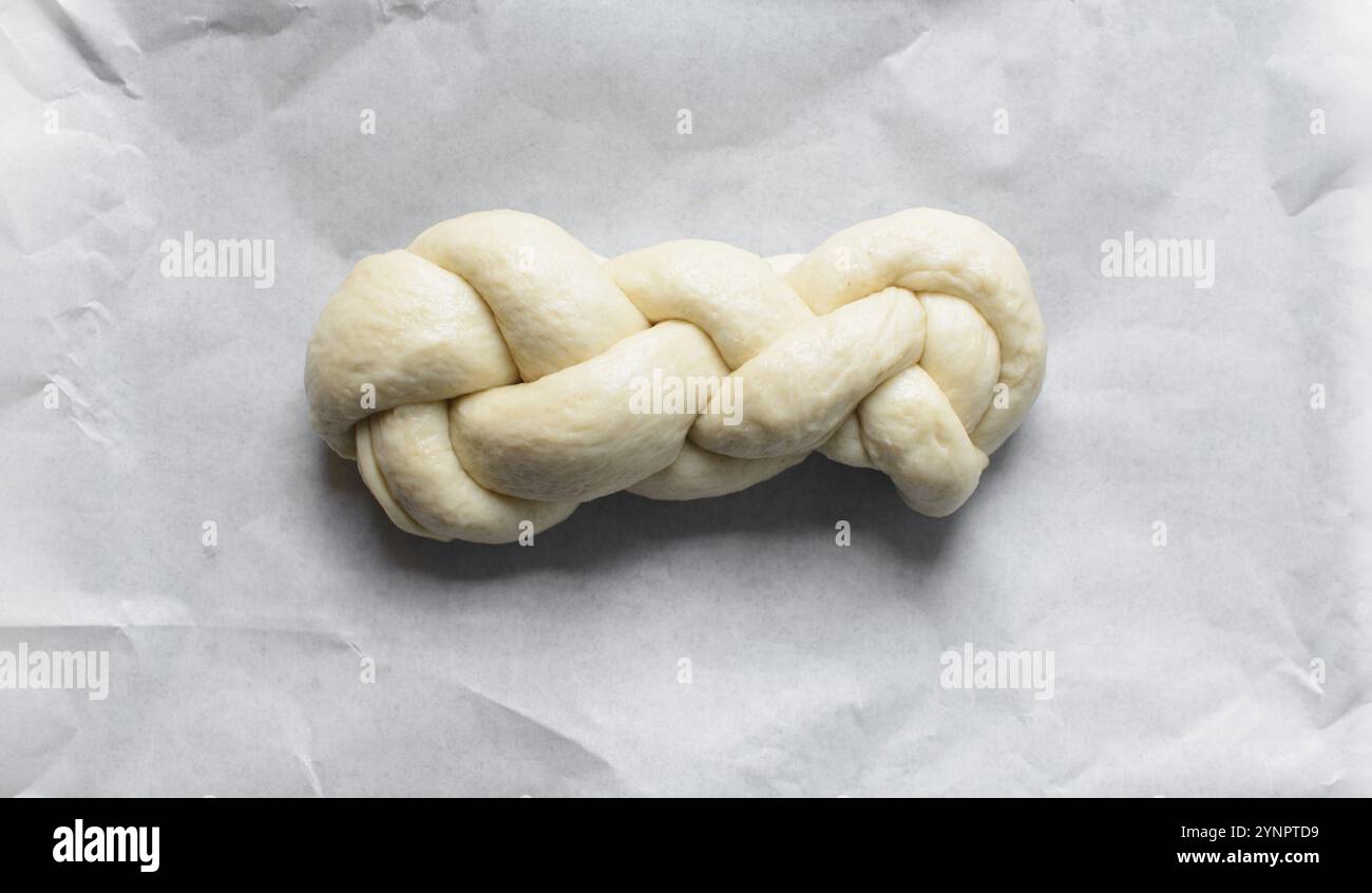 Overhead view of 2 strand challah rising on a parchment lined baking ...