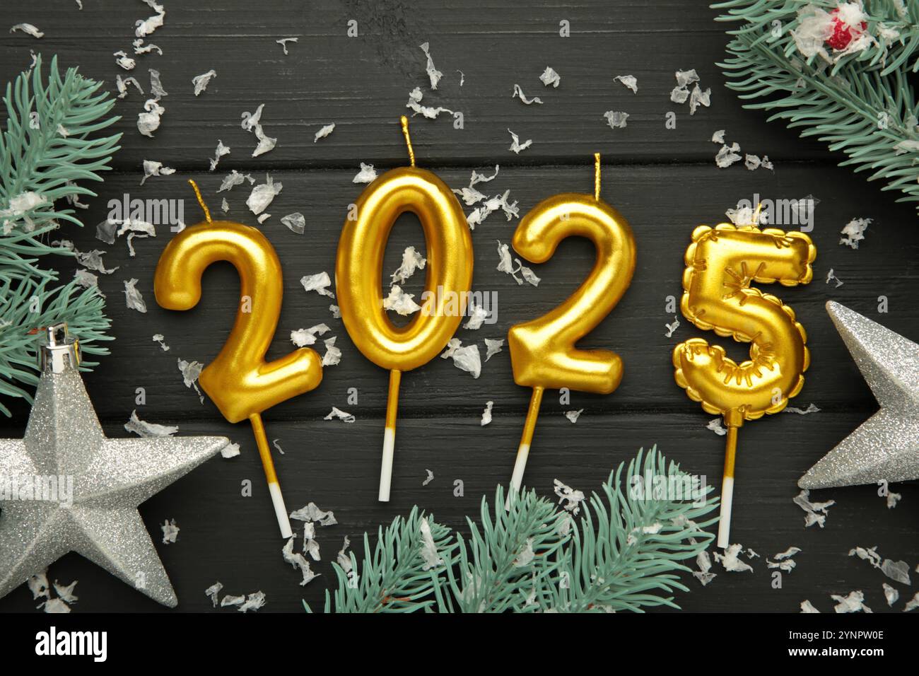 Numbers of year 2025 made by gold candles with fir tree on black wooden ...