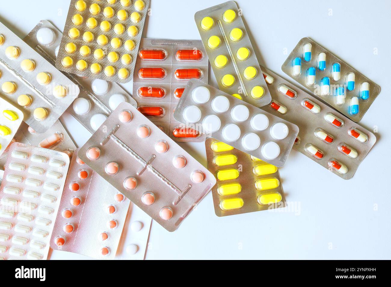 Various medication capsules, tablets are spread out on white surface ...