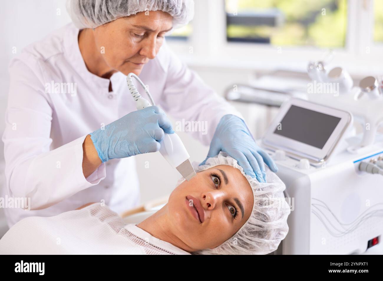 Young female client experiencing facial skin peeling with ultrasonic ...