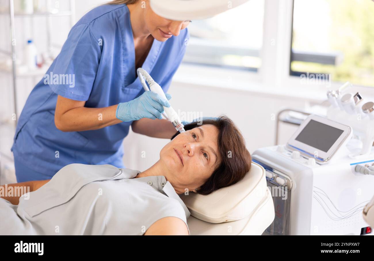 Mature woman getting facial deep hydration procedure from experienced ...