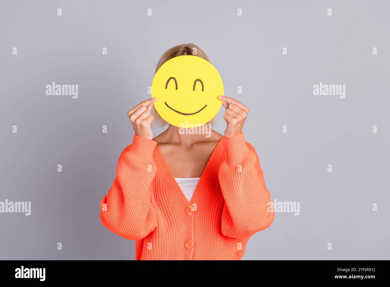 Portrait of nice young girl hide face behind emoticon smiley orange ...