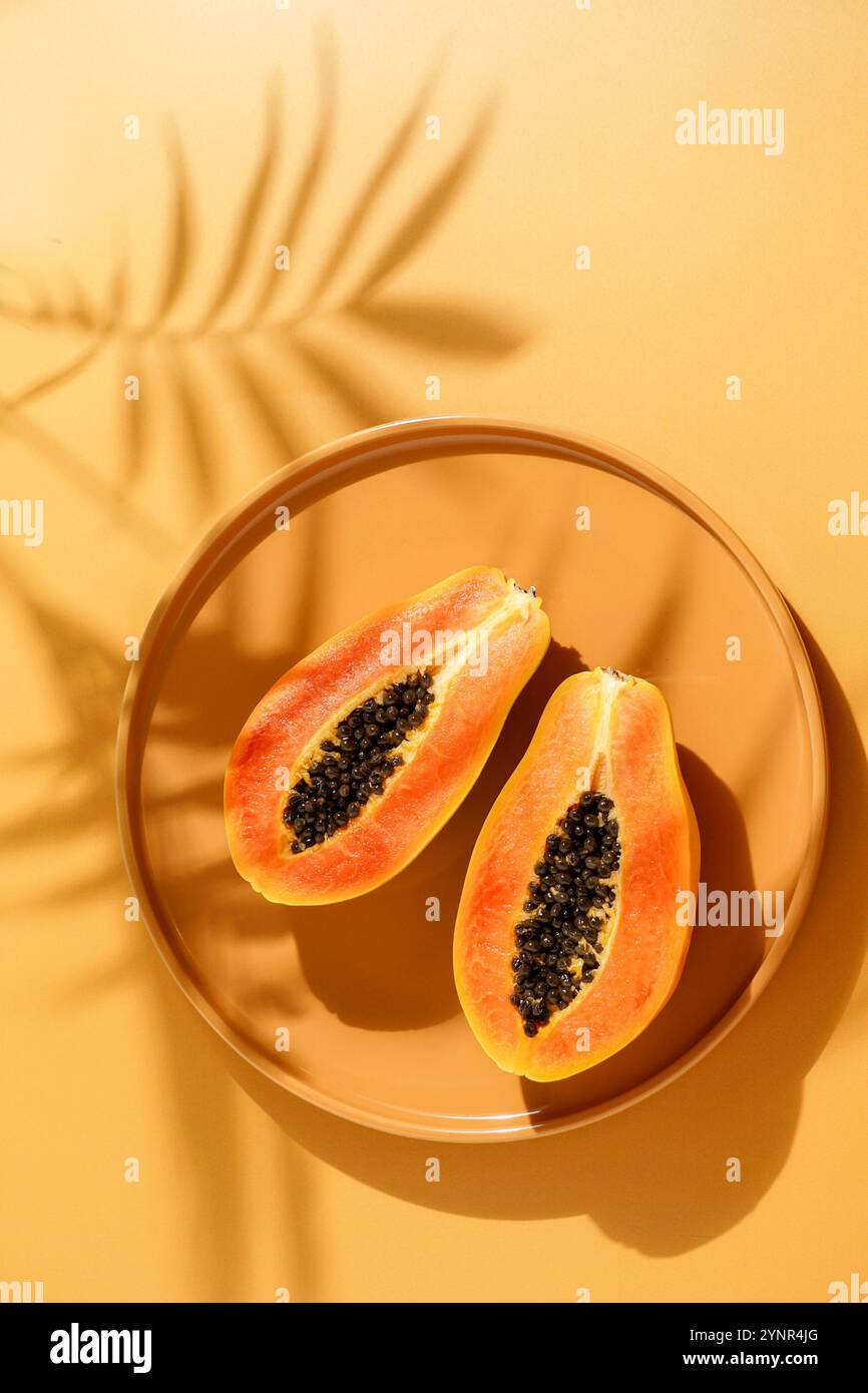 fresh, ripe papaya sliced open on orange background, harsh sunlight ...