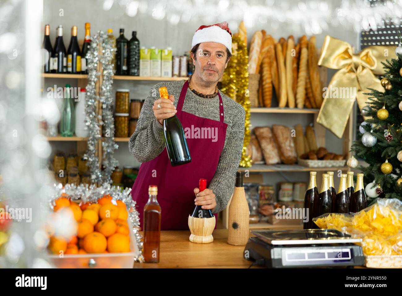 Friendly adult male shop seller posing behind counter with alcoholic ...