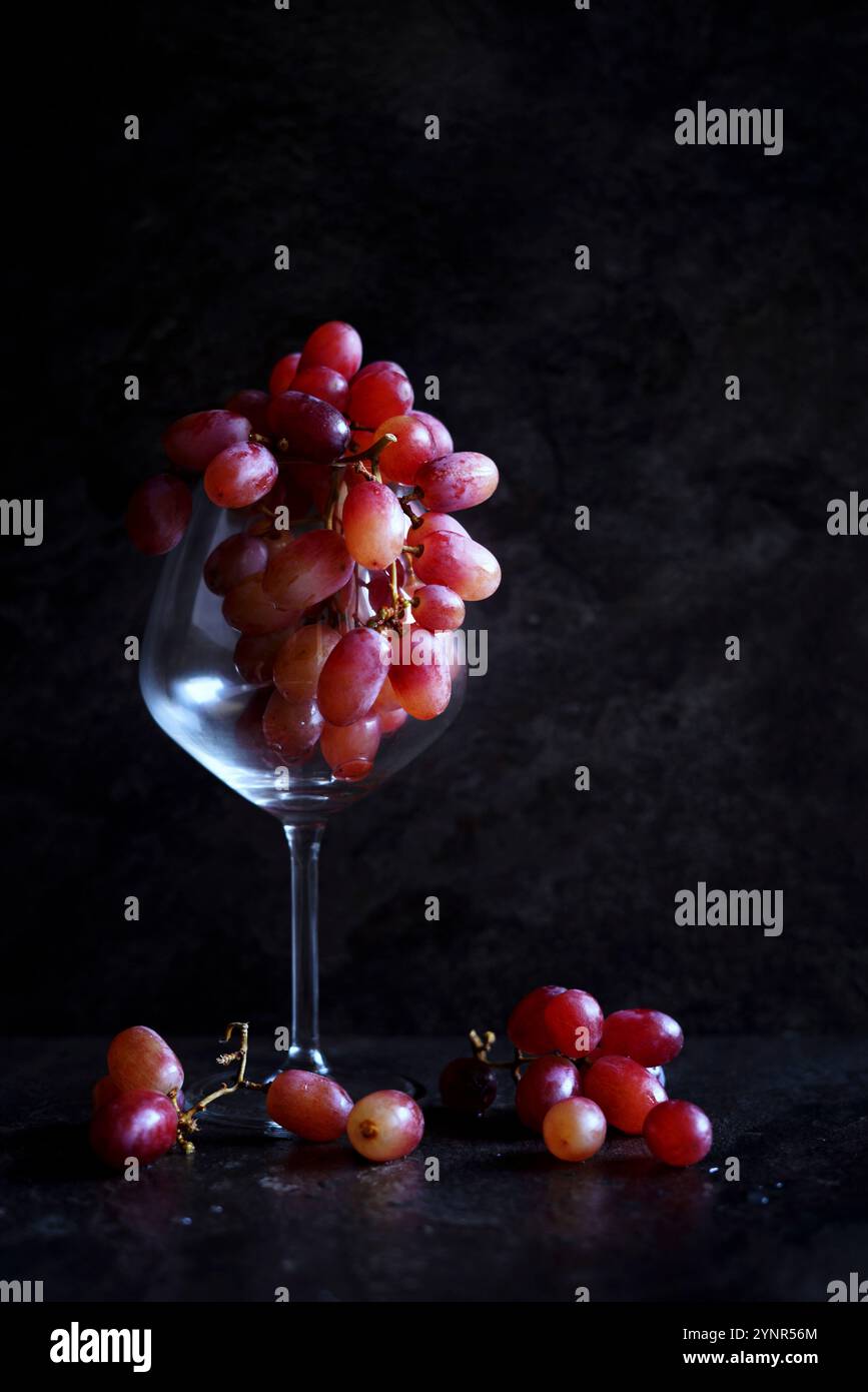 Red grapes in wine glass. Still life on dark background Stock Photo - Alamy