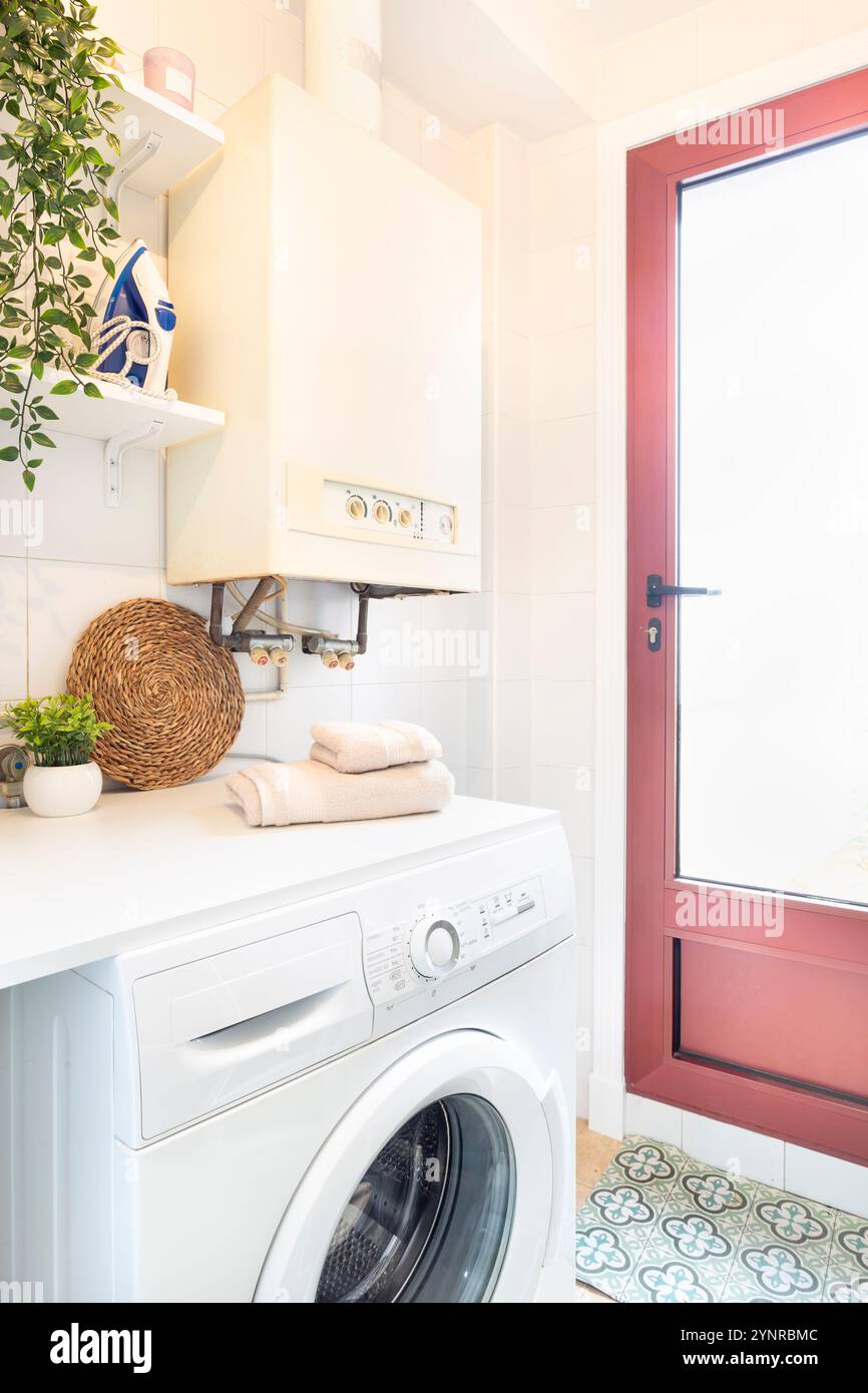 Laundry room with white washing machine, gas heater, iron and red glass ...
