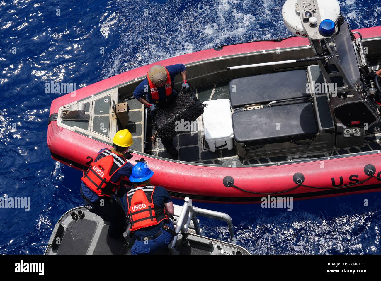 U.S. Coast Guard Petty Officer Second Class David Rind passes a bale of ...