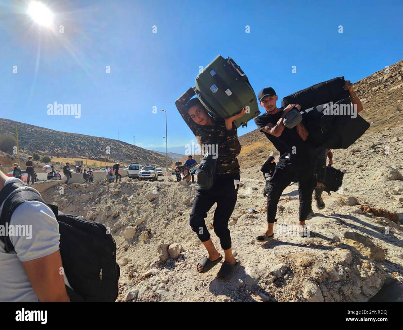 Syrians carry their luggage as they cross on foot into Syria through a ...