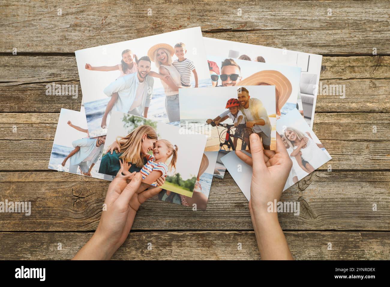 Woman with different photos in open photo album at wooden table, top ...